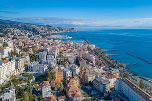 Paisagem costeira urbana com edifícios densos, um porto de iates e mar azul cristalino.