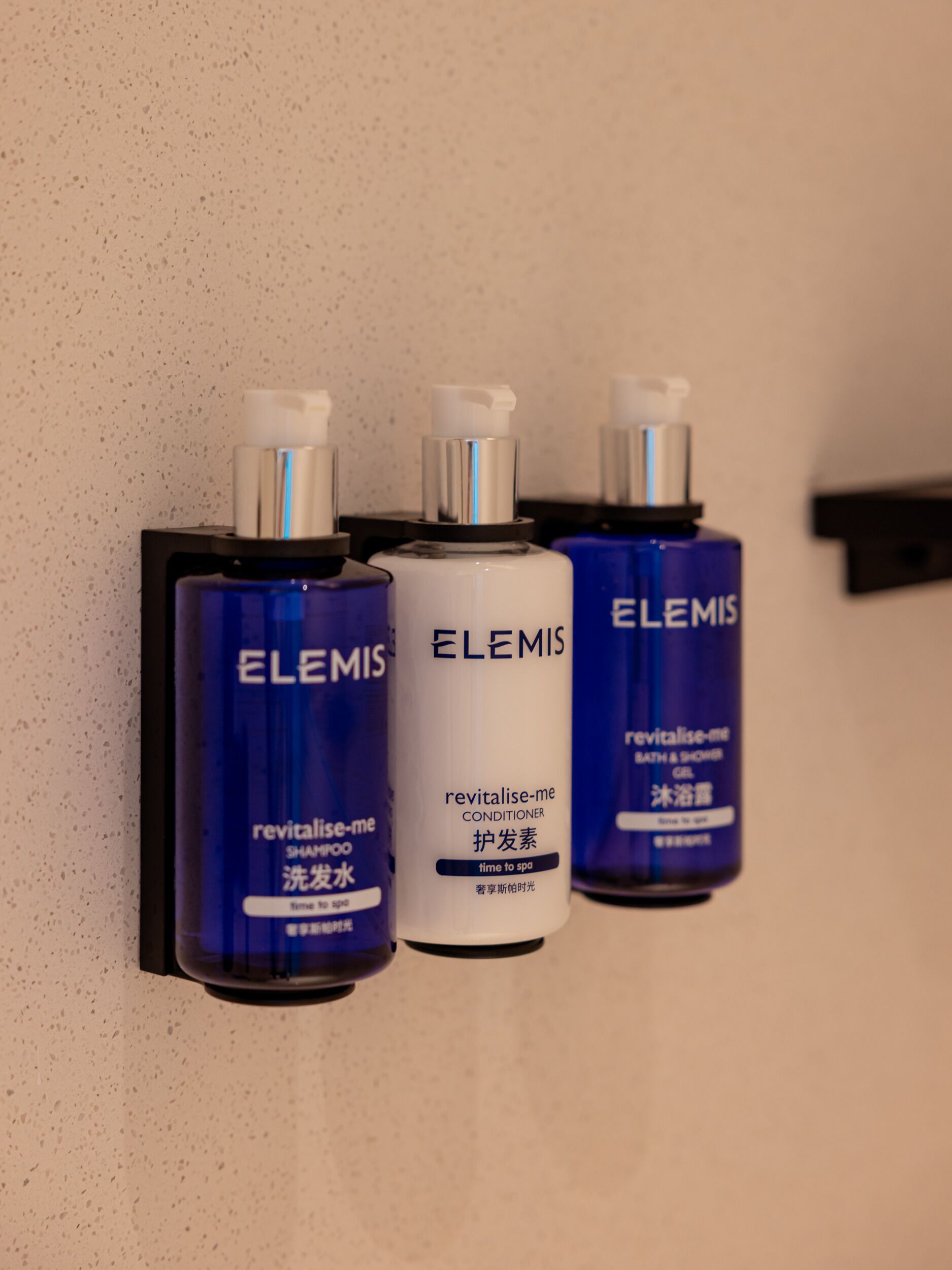 Três produtos Elemis em uma parede.
