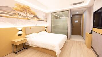 Quarto de hotel moderno com cama, mesas de cabeceira, um quadro na parede, uma porta deslizante e uma televisão.