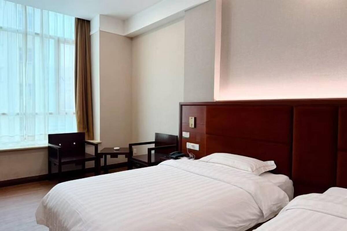 Quarto de hotel com duas camas, uma escrivaninha e uma cadeira.