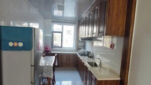 Uma cozinha com armários de madeira, geladeira de aço inoxidável, uma janela e uma mesa com cadeiras.