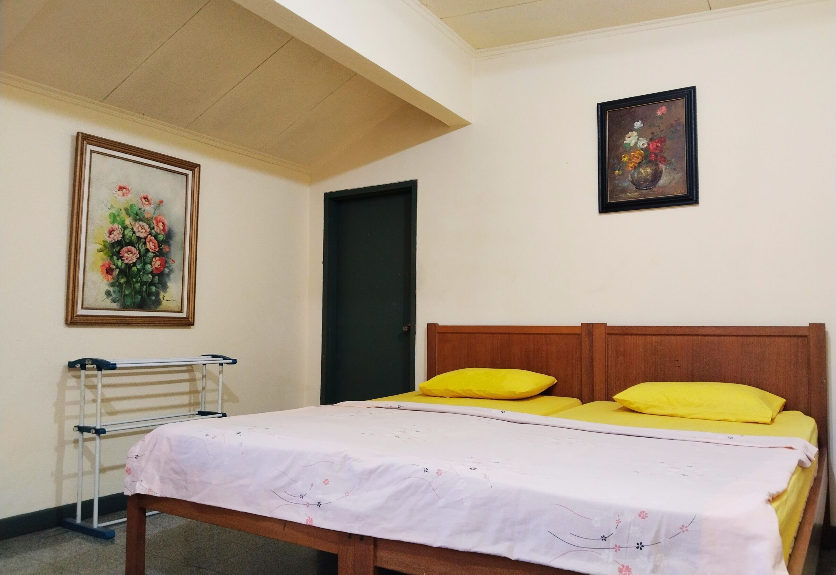 Quarto com cama, radiador, porta e duas molduras na parede.