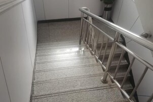 Escada com corrimãos de metal e guarda-corpo, levando a um andar superior.