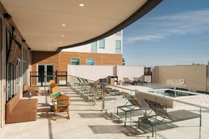 Terraço no telhado com piscina, espreguiçadeiras e guarda-corpo de vidro.