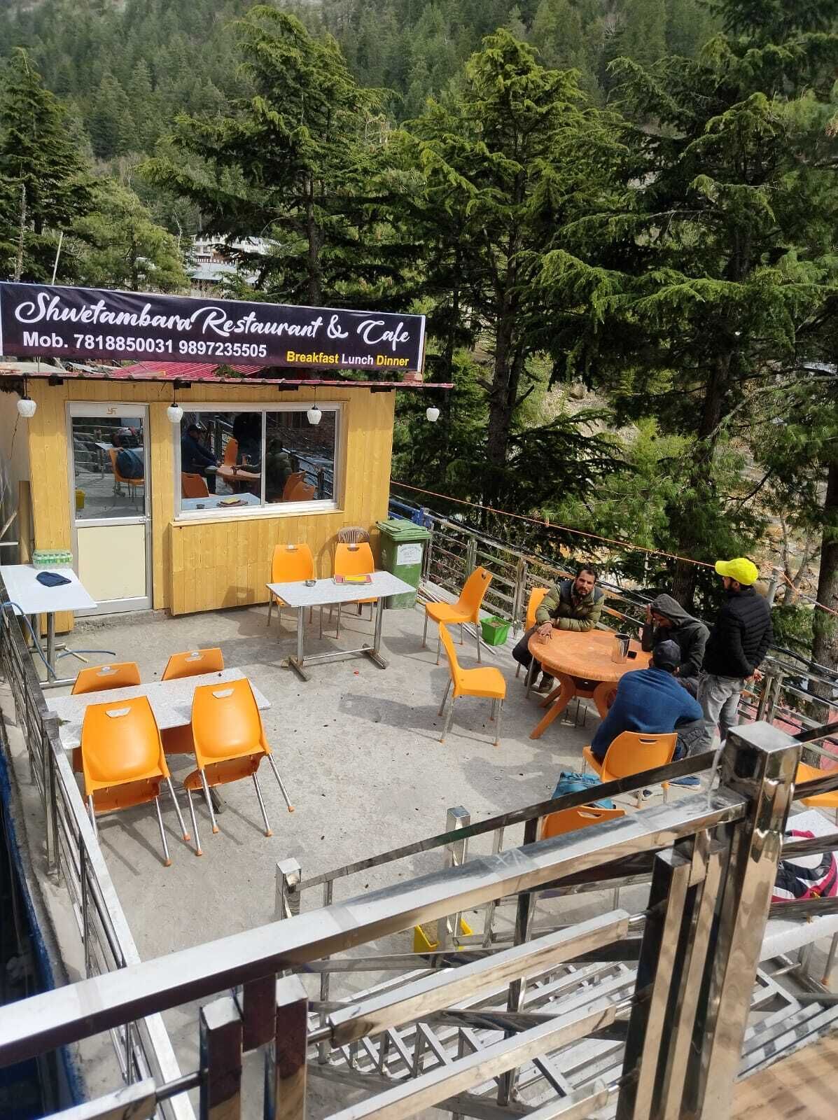Restaurante e Café Shwetambaram com área externa e vista para a floresta ao redor.