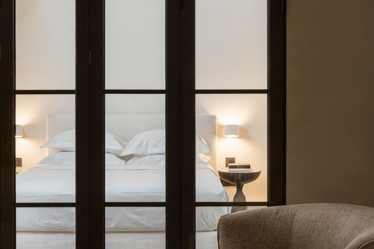Quarto com cama, abajures e uma cadeira.