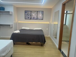 Quarto moderno com cama, mesa de cabeceira, prateleira na parede e um espelho grande.