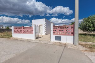 Uma entrada murada com um edifício branco e um portão vermelho.
