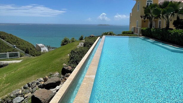 Piscina com vista clara do oceano e uma ilha ao longe.