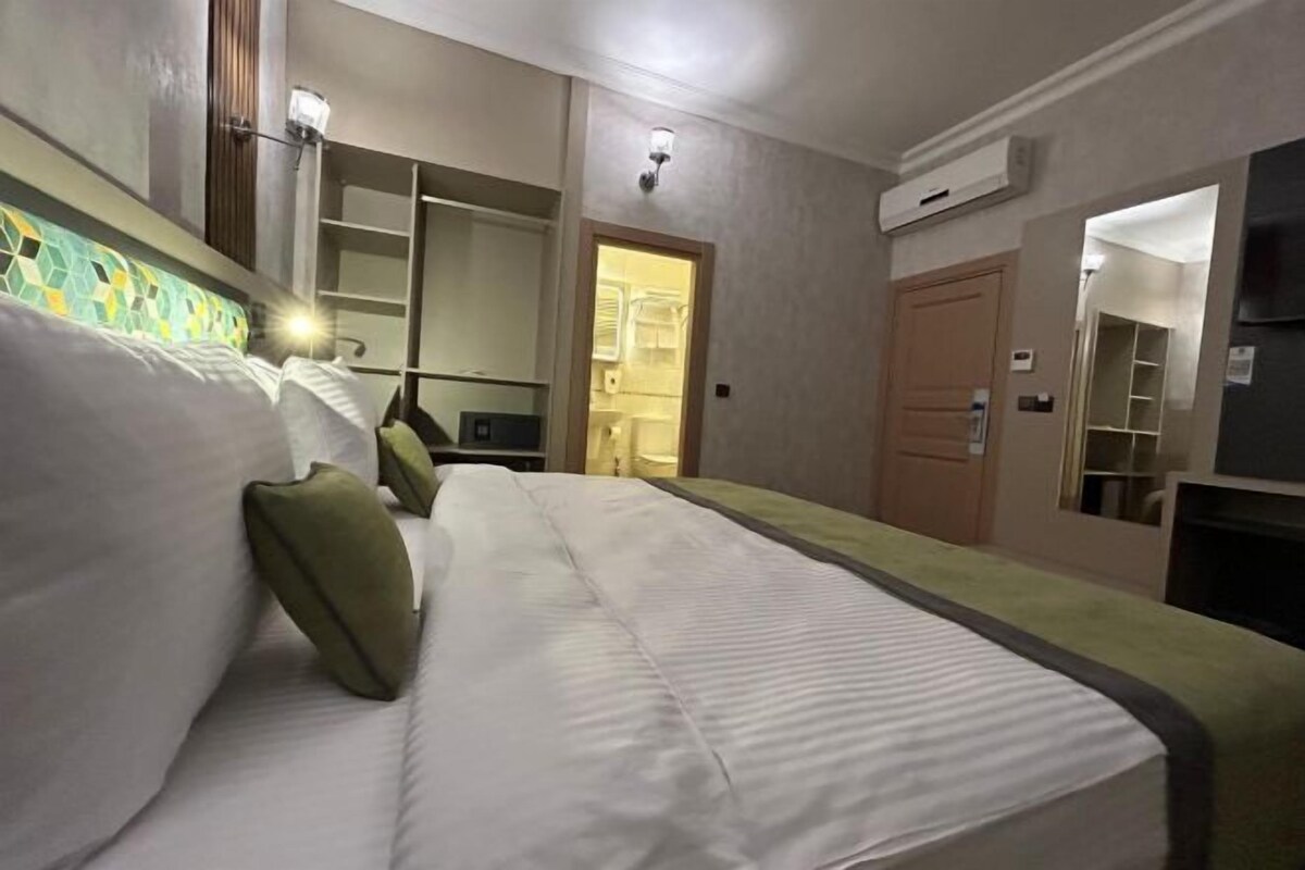 Quarto de hotel com cama, guarda-roupa, espelho e televisão.