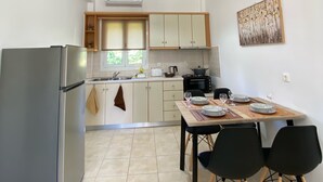 Cozinha compacta com geladeira, fogão, micro-ondas e uma mesa de jantar para quatro pessoas.