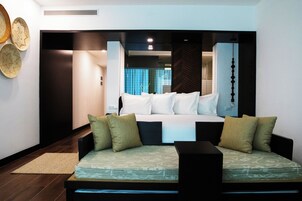 Quarto de hotel moderno com uma cama grande, um sofá e vista para o banheiro.