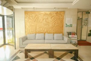 Uma área de recepção com sofá, mesa de centro e painel decorativo.