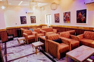 Um hall de hotel com assentos confortáveis, piso de mármore e obras de arte nas paredes.