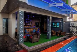 Uma área de bar interna com piscina, balcão e assentos.