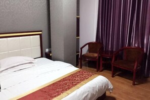 Quarto de hotel com uma cama, duas cadeiras de madeira, um tapete vermelho e uma cortina.