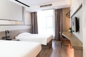 Quarto de hotel com duas camas, uma escrivaninha, uma televisão e uma janela com cortinas.
