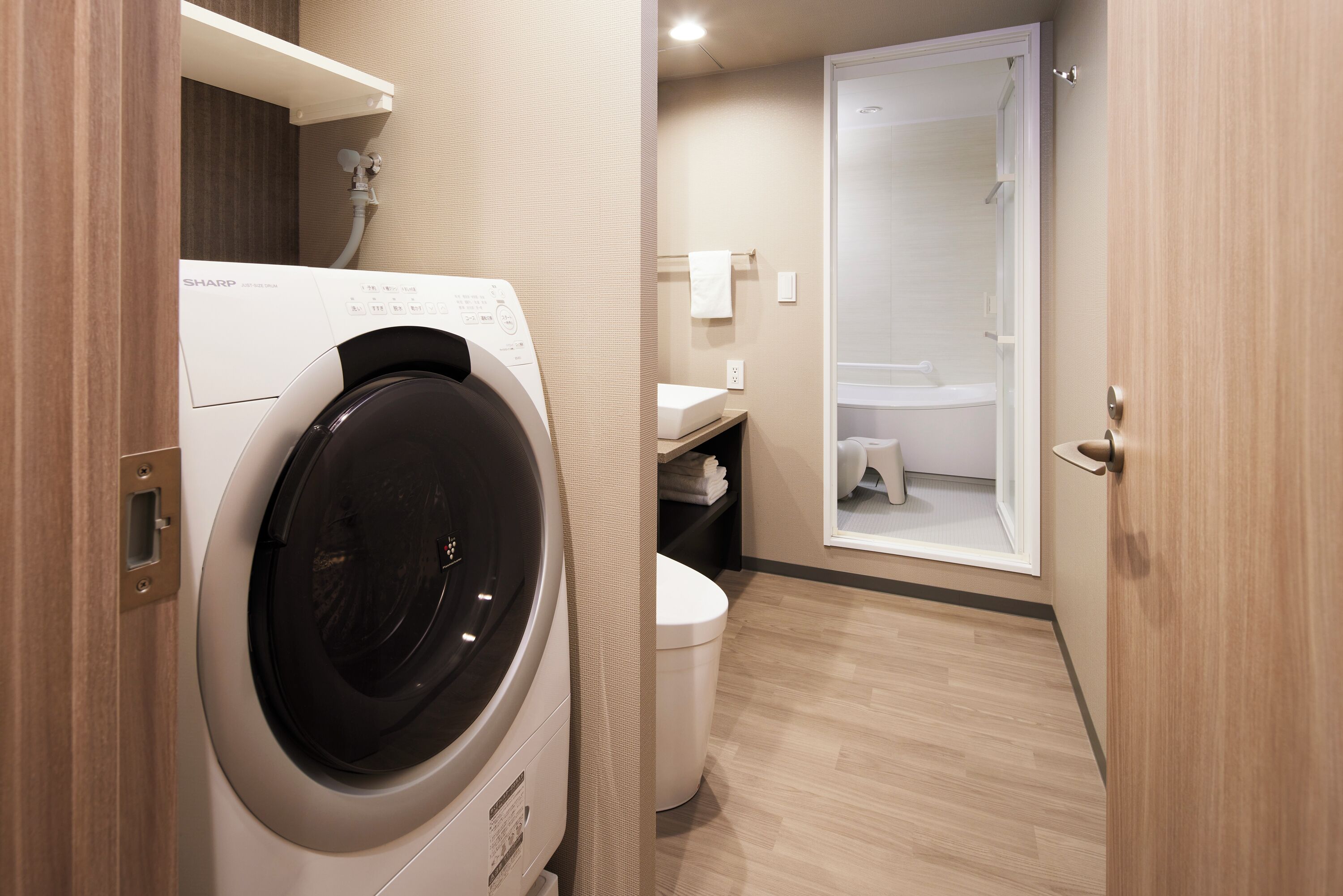 Casa de banho compacta e moderna, com máquina de lavar roupa, sanita e zona de duche.