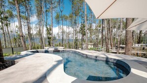 Uma piscina com design curvo, rodeada por árvores e uma vista clara do céu.