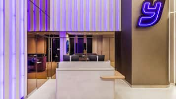 Uma área de recepção com design moderno, com balcão de atendimento, espaço para sentar e um letreiro de neon.