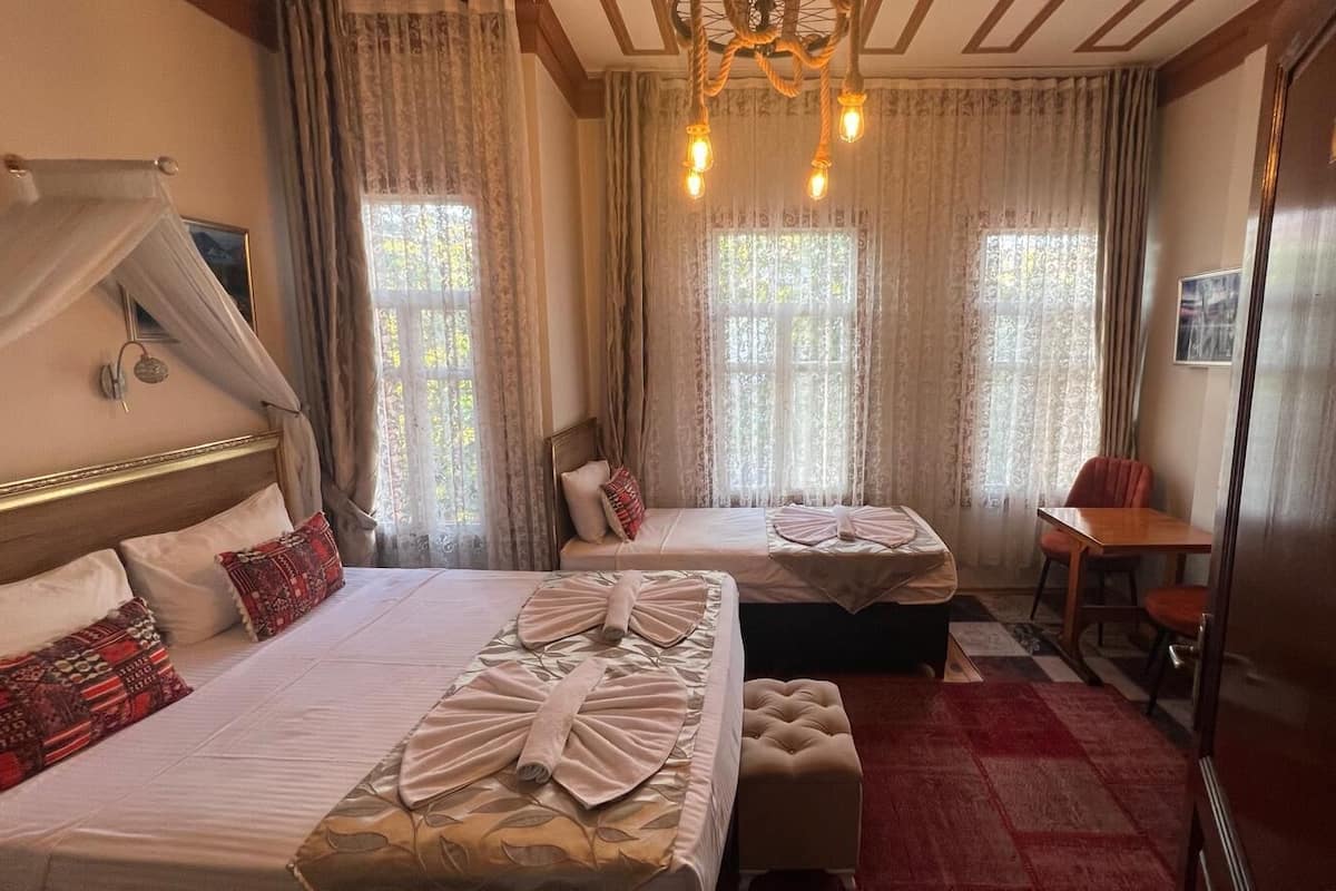 Quarto de hotel com duas camas, um espaço de refeições e um candelabro.