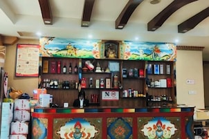 Balcão de recepção com um mural colorido, um relógio e diversos objetos nas prateleiras.