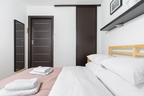 Quarto de hotel com cama, guarda-roupa e uma prateleira com um quadro.