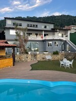 Uma casa moderna de dois andares com piscina, degraus de pedra e área de estar externa.