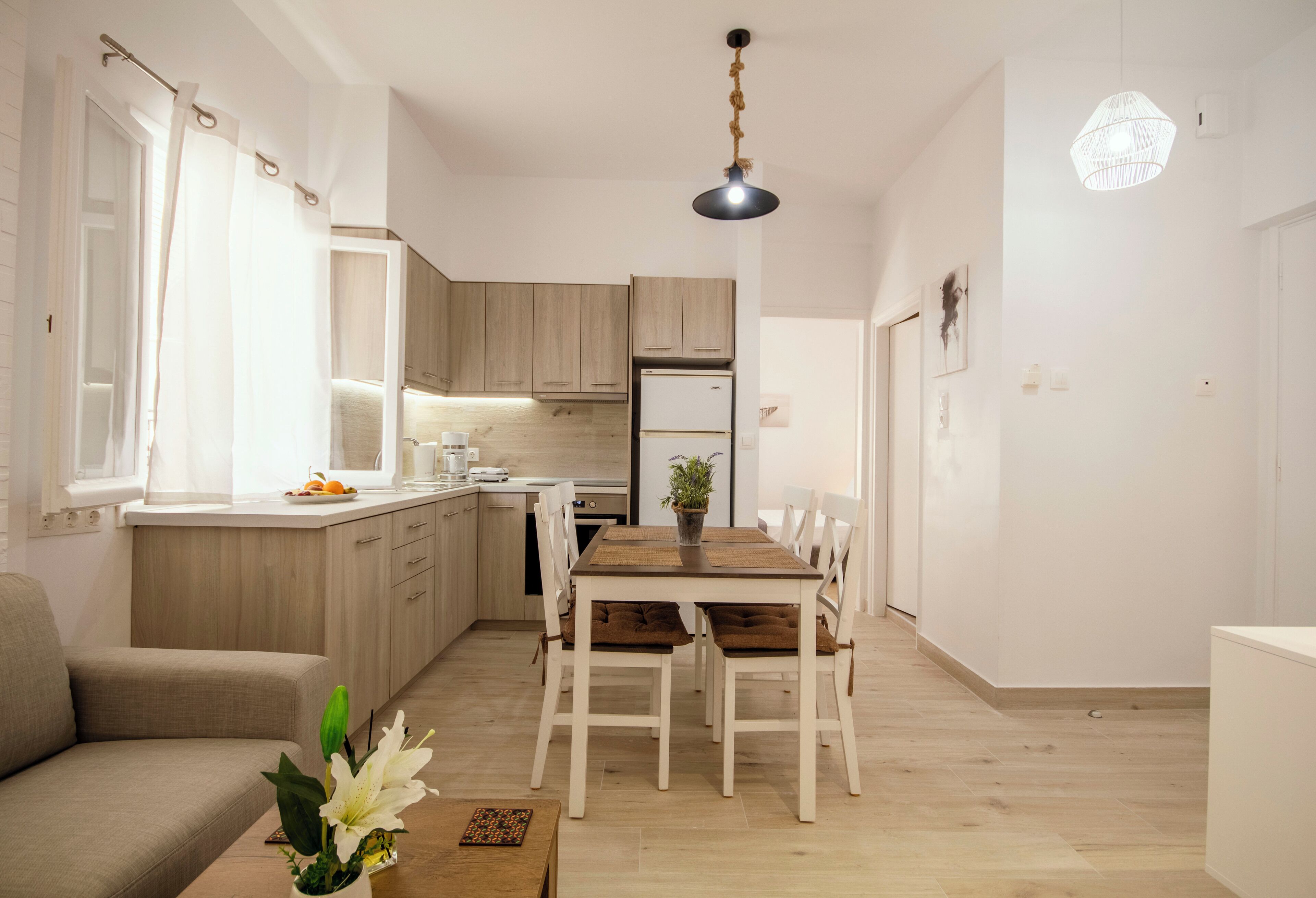 Uma cozinha moderna com armários de madeira, uma mesa de jantar com cadeiras e um lustre.