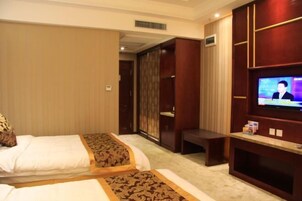 Quarto de hotel com duas camas, televisão e guarda-roupa.