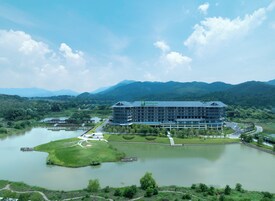 Um hotel Holiday Inn com design moderno, rodeado por um lago e montanhas.