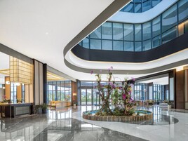 Um hall moderno com um jardim central, teto curvo e grandes janelas.