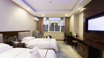 Quarto de hotel com duas camas, uma mesa, uma televisão e janela com vista para a cidade.