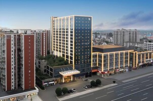 Hotel moderno com vários andares, um átrio central e área de estacionamento.