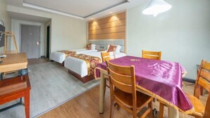 Quarto de hotel com uma cama, uma escrivaninha e uma mesa de jantar.