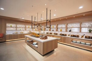 Cozinha moderna com ilha central, iluminação pendente e prateleiras embutidas com utensílios de cozinha.