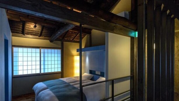 Quarto com cama, janela com vista e teto de madeira.