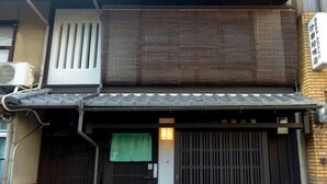 Um edifício japonês tradicional com telhado de telhas, porta deslizante e pequena área de estar externa.