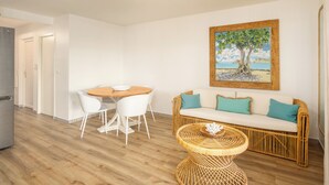 Uma sala de estar moderna com um sofá, uma mesa de jantar e cadeiras. Há um quadro na parede e uma luminária no teto.