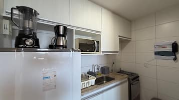 Cozinha equipada com geladeira, cafeteira, micro-ondas e fogão a gás.