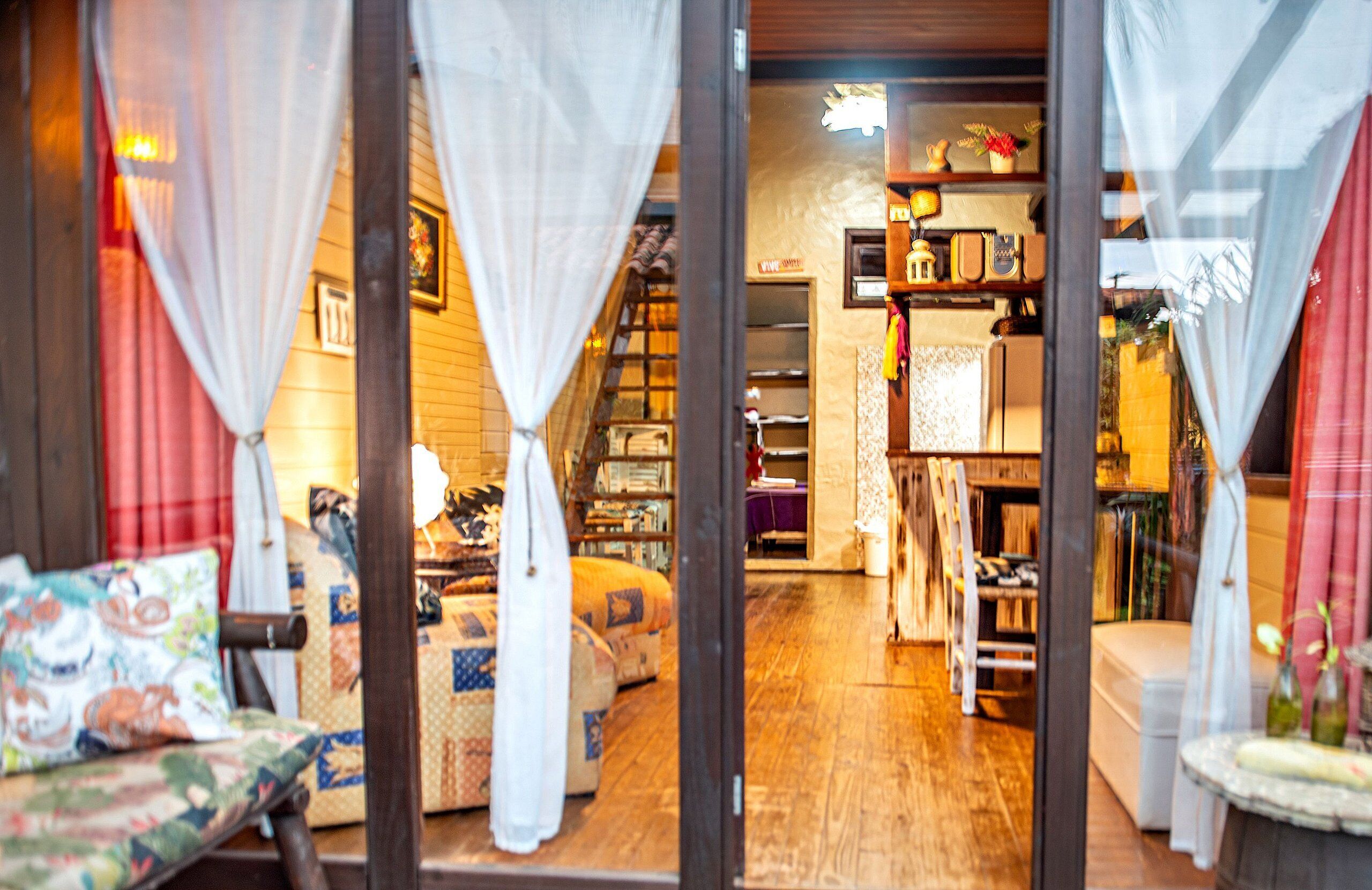 Um interior acolhedor com piso de madeira, um sofá com almofada floral e uma estante de livros.