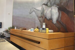 Bancada de recepção com uma grande pintura abstrata na parede ao fundo.