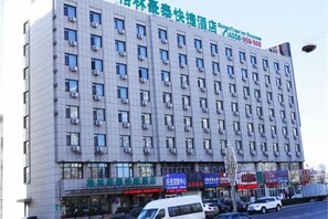 Um hotel com vários andares, fachada uniforme, várias janelas e diversos estabelecimentos comerciais no térreo.