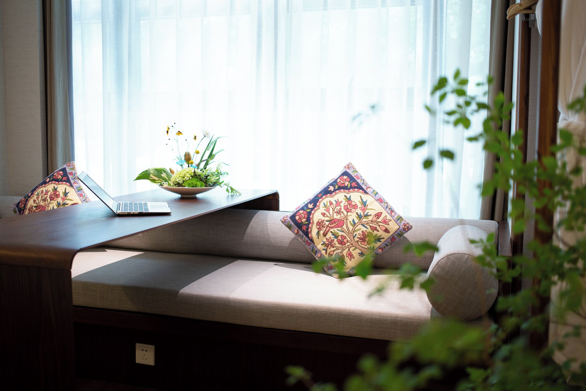 Quarto moderno com sofá, um laptop e uma planta decorativa.