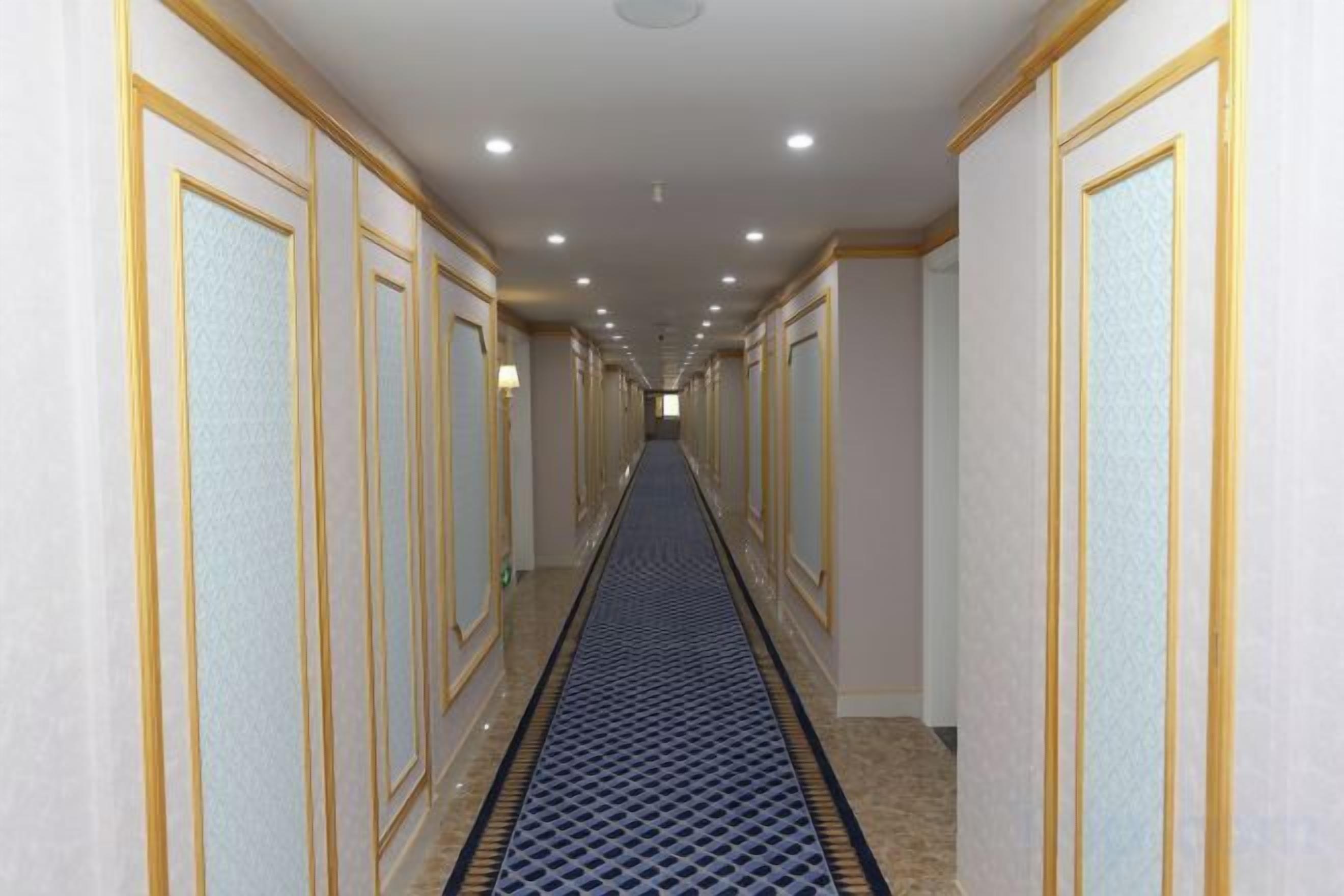 Um corredor comprido e estreito, com portas em ambos os lados, que dá acesso a quartos.