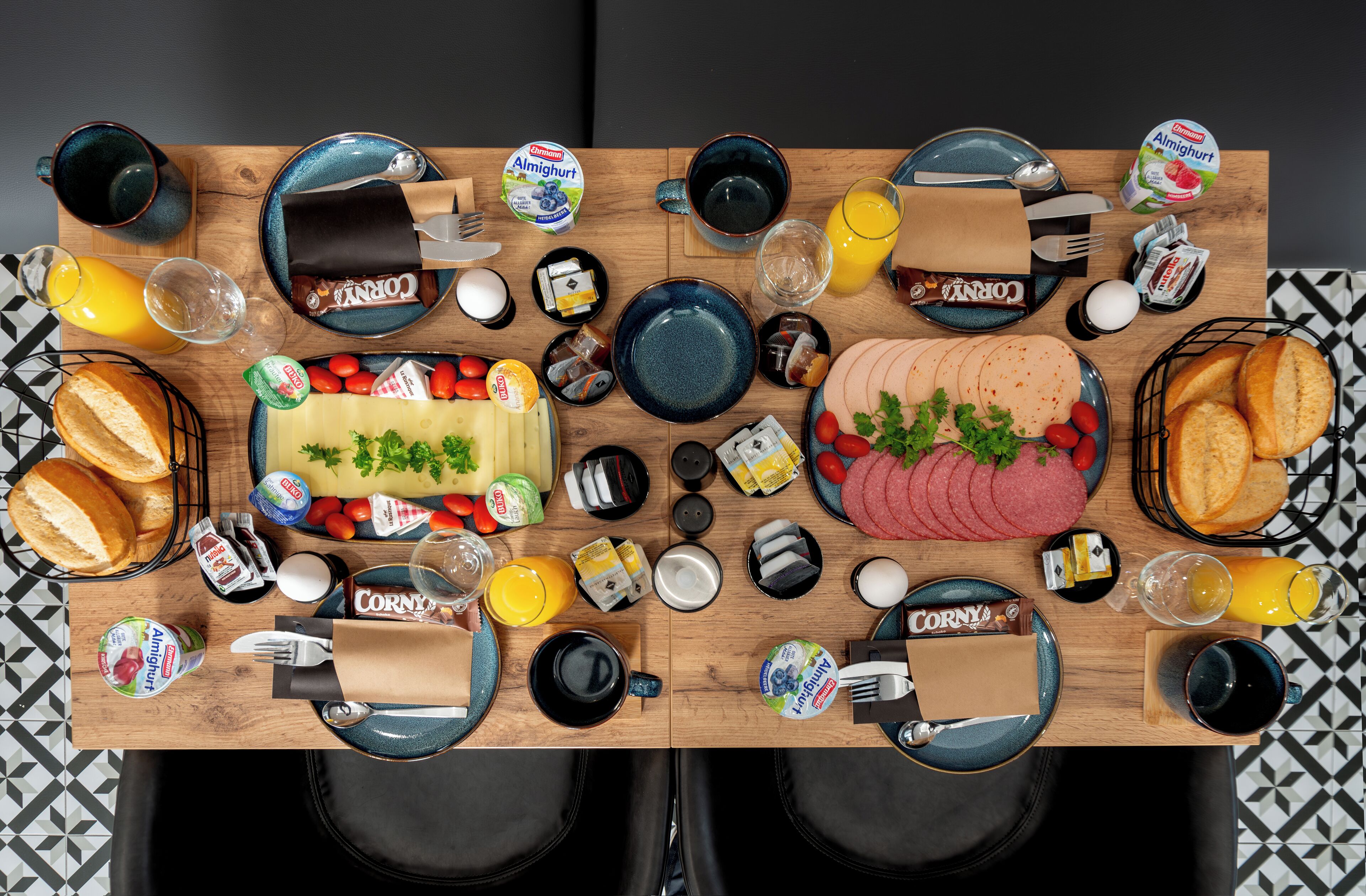 Uma mesa de café da manhã com diversos alimentos, bebidas e utensílios.