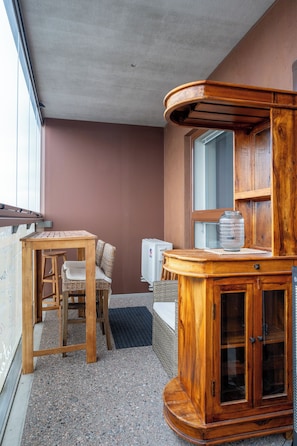 Quarto nos fundos com mesa de madeira, cadeira de vime e armário com portas de vidro.