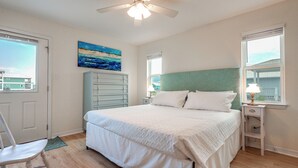 Quarto com cama, mesa de cabeceira, cadeira, quadro e janela.