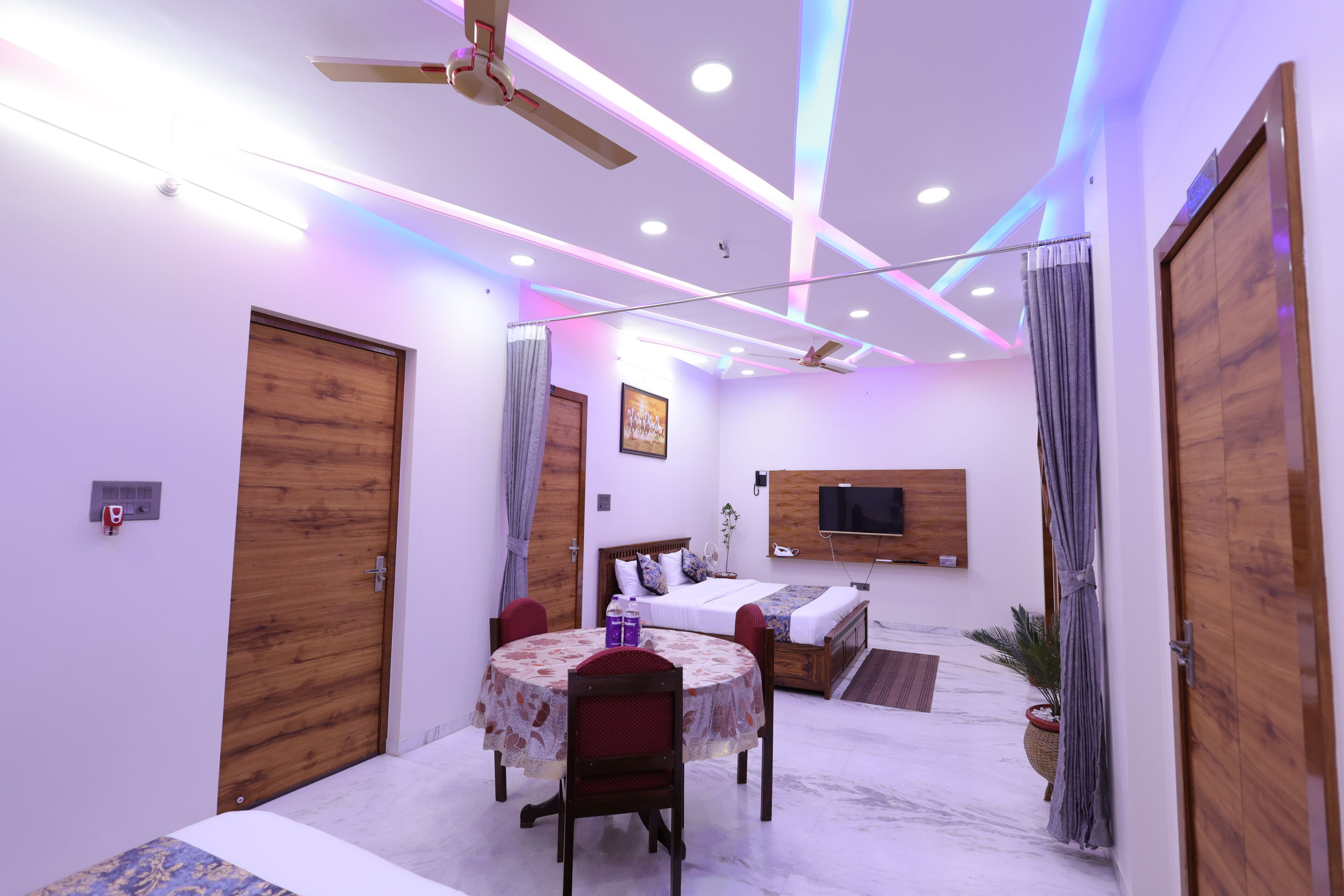 Quarto moderno com cama, mesa de cabeceira e televisão fixada na parede.