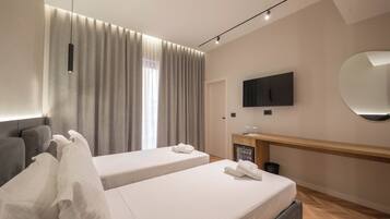 Quarto de hotel moderno com duas camas, televisão de tela plana, mesa de cabeceira de madeira e uma janela grande com cortinas.